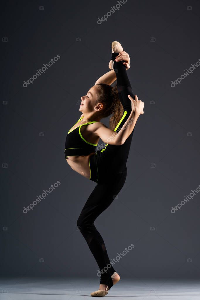 Niña flexible haciendo acrobacias mientras está de pie sobre sus manos ...