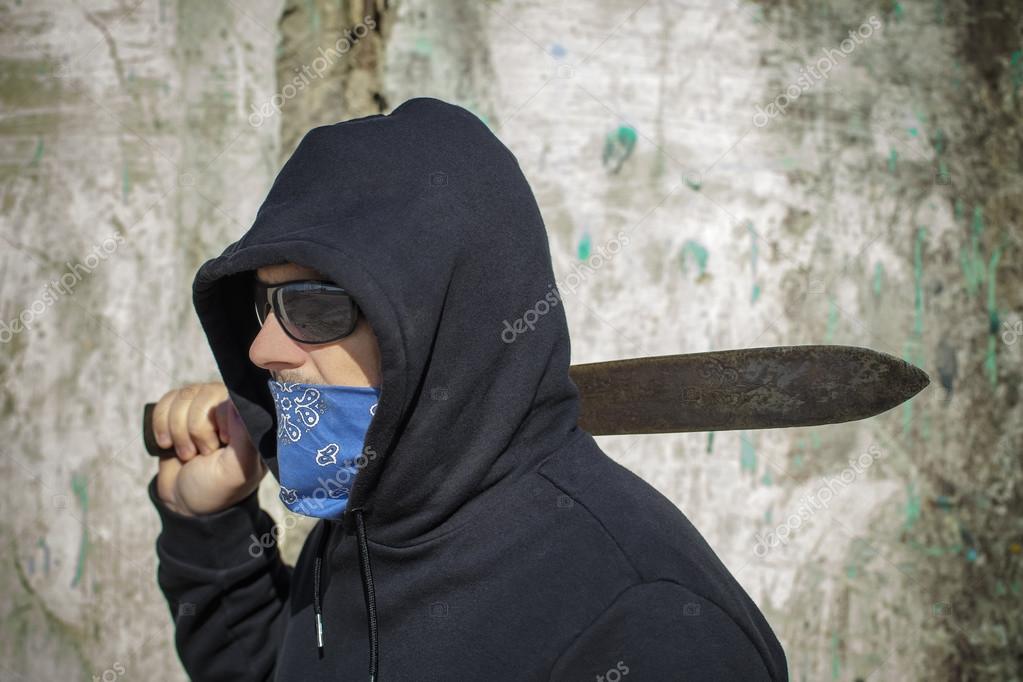 Hombre con un machete en el hombro sobre un fondo de pared 2024