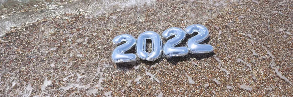 Silver numbers 2022, inflatable figures on the wet sea sand, close-up ...