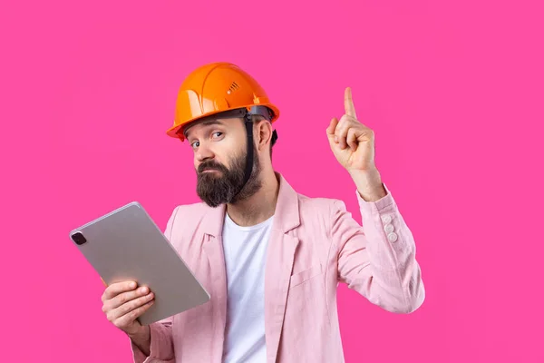 Portrait of young construction engineer wear orange hard hat, in a pink ...