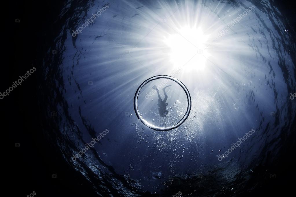 A Diver circled by bubble ring inside of a Snell's Window with Sun ...