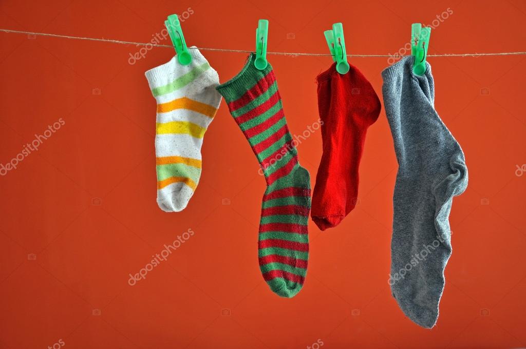 Different types of striped socks hanging on a rope isolated on red ...