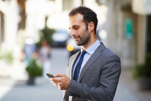 Business man typing sms on mobile phone in street - Stock Image ...