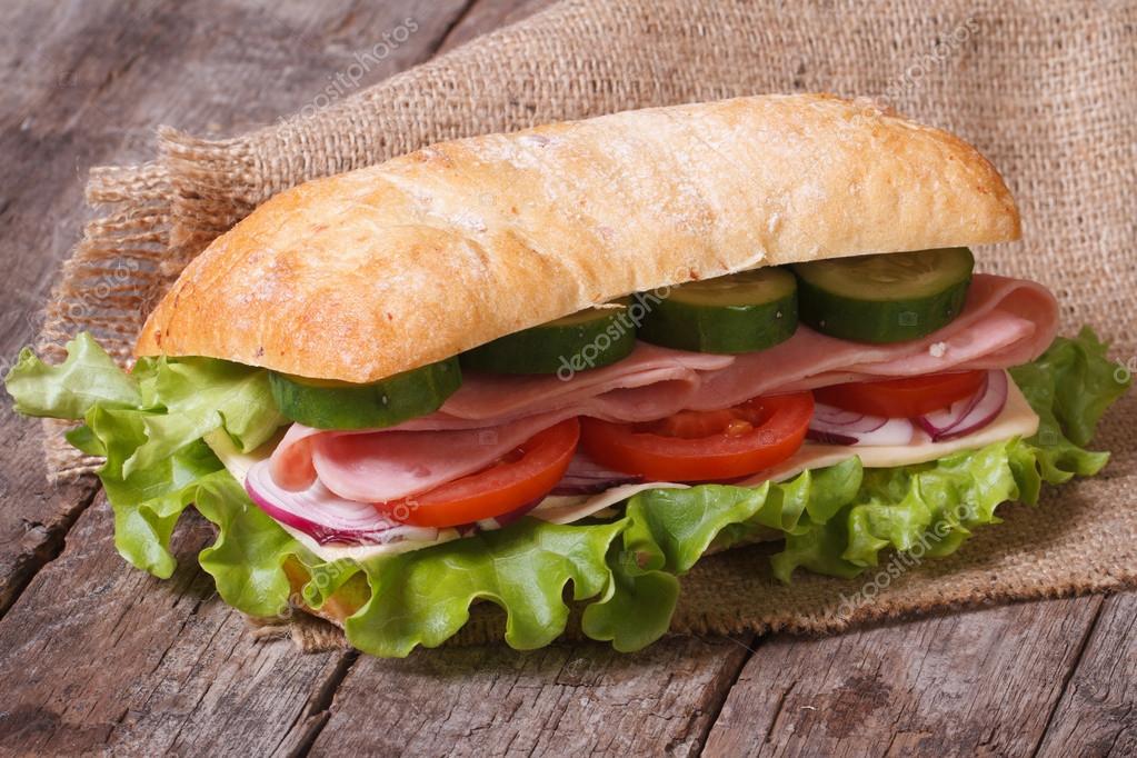 Ciabatta sandwich with ham and vegetables on an old wooden table Stock ...