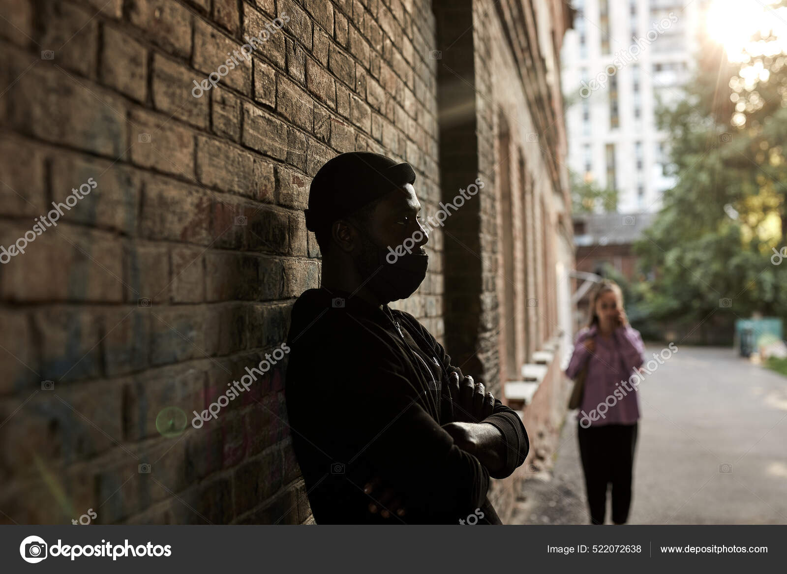 Suspicious criminal is standing at street waiting for female victim ...