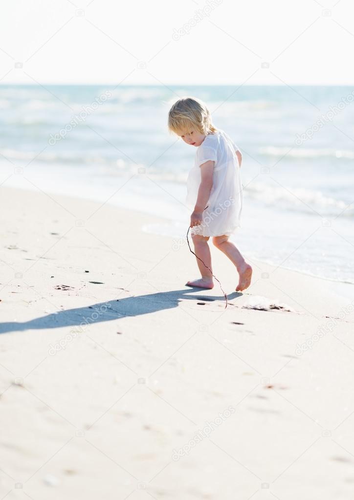 Lonely baby playing on sea shore Stock Photo by ©CITAlliance 30059549