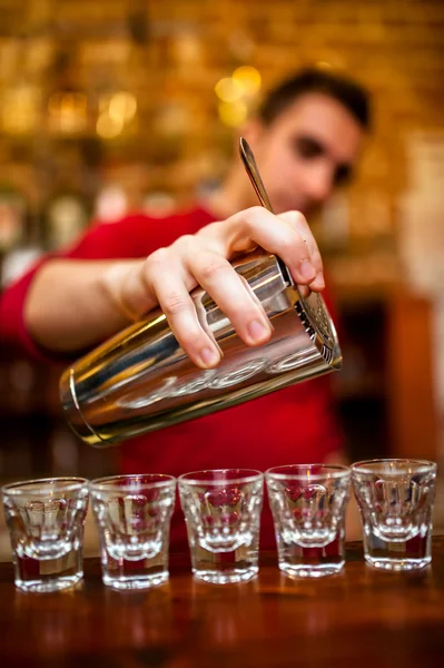 Close-up of Barman pouring alcoholic drink and cocktails into small ...