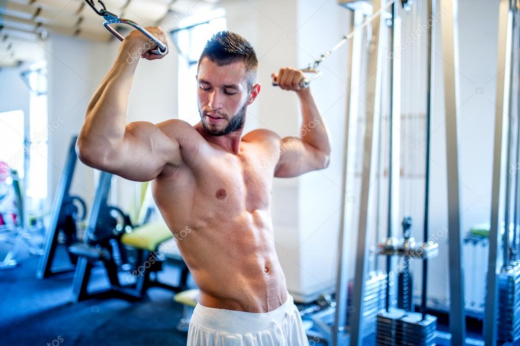 Trainer, bodybuilder working out the biceps and the abs in gym on a ...