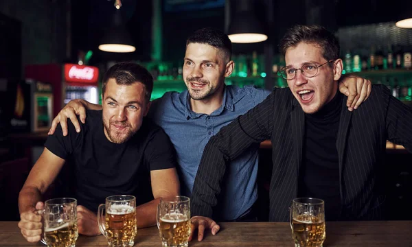 Three sports fans in a bar watching soccer. With beer in hands. - Stock ...