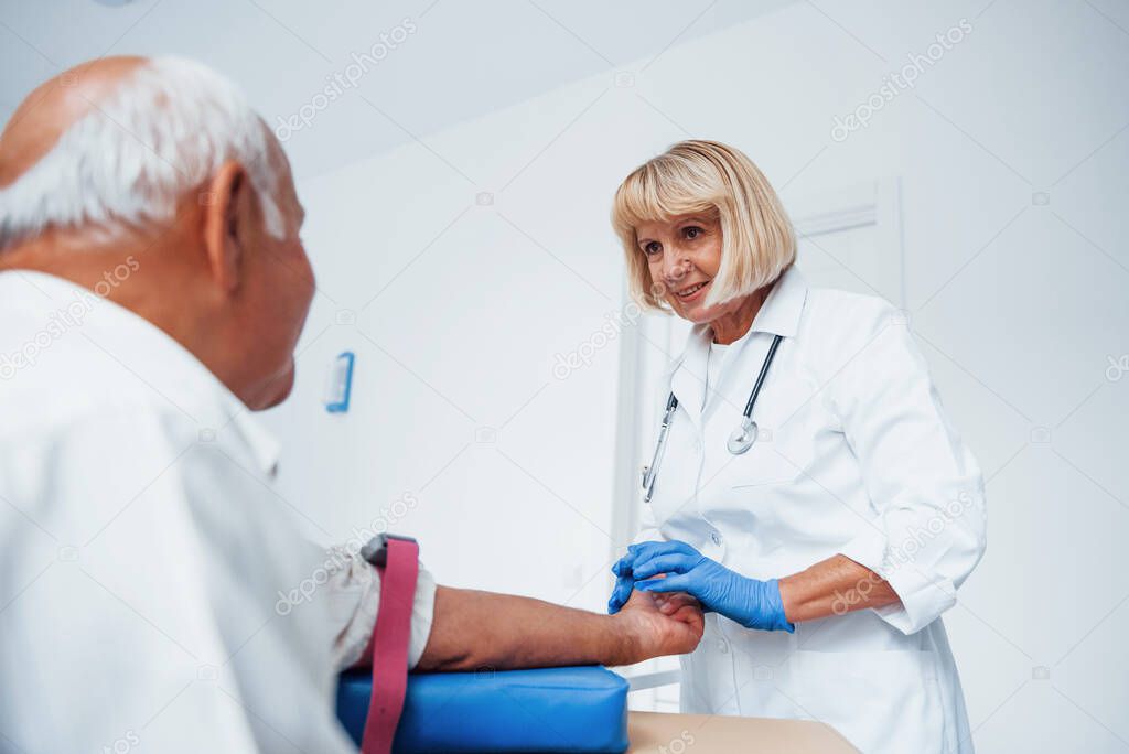 Doctora preparándose para inyectar a un paciente masculino mayor en la ...