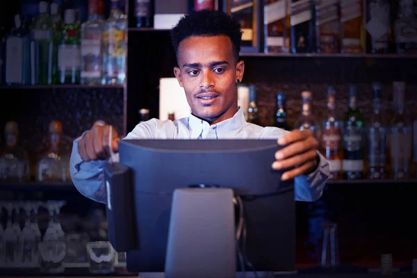 African bartender registrating new order by cash register. African ...