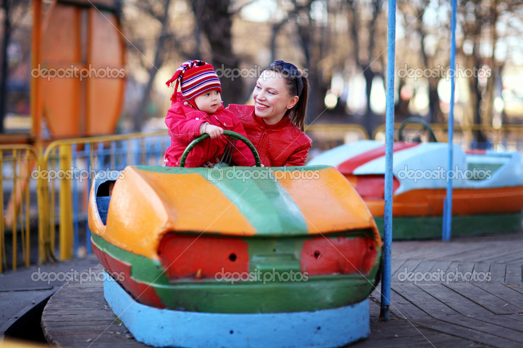 Mom and young daughter ride on the carousel, in small car — Stock Photo ...