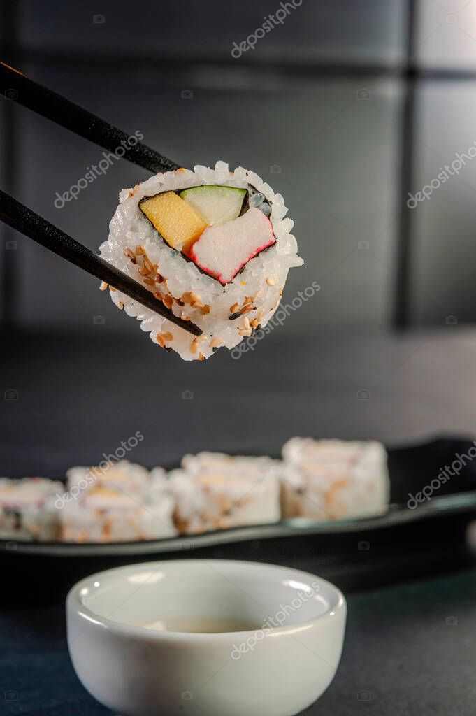 Uramaki con pepino, fruta de mango y palitos de cangrejo en palillos ...