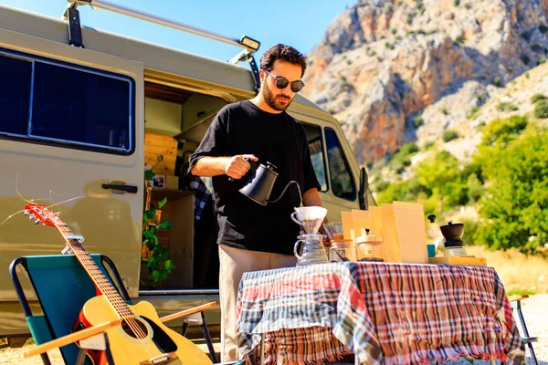 young man relaxing in rv, camping in a trailer mountain background ...