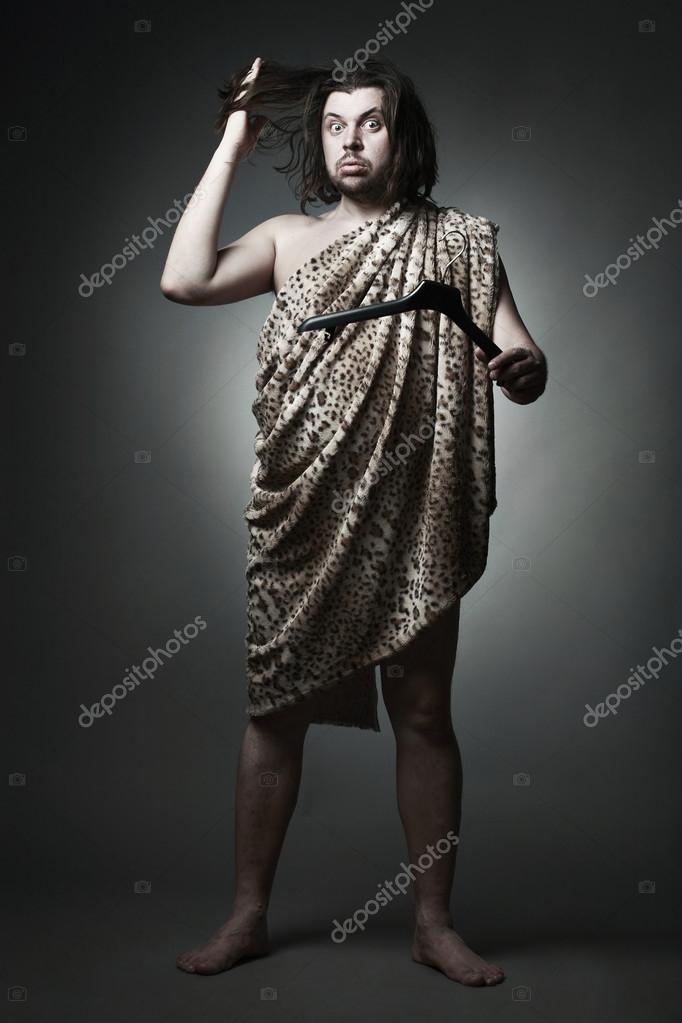Wild man in leopard skin hold empty hanger, and comb his hair with hand ...