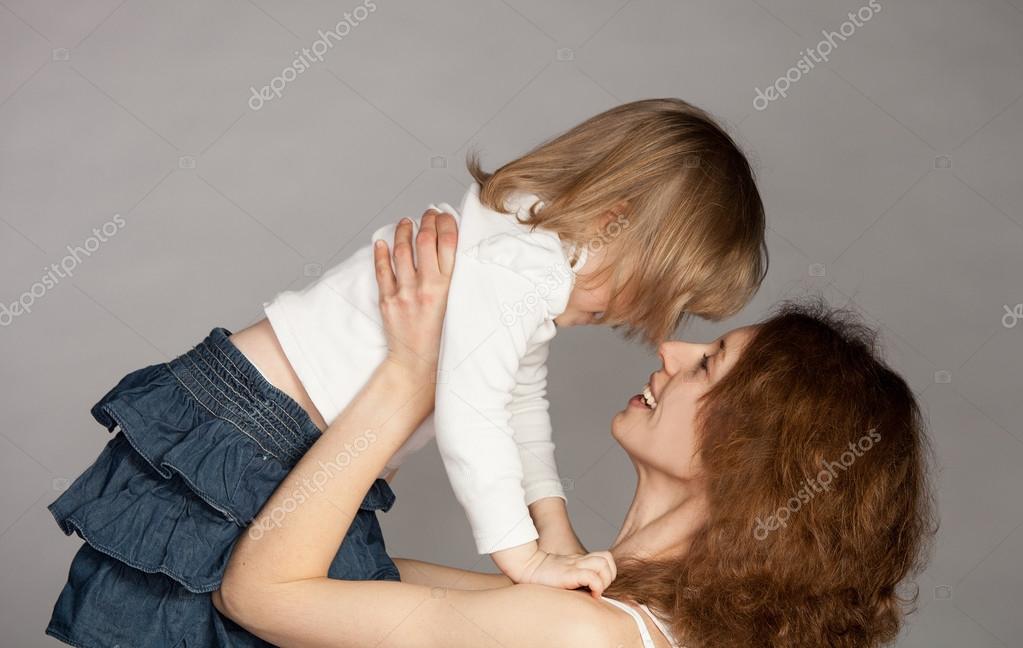 Smiling young mother raising her little daughter — Stock Photo ...
