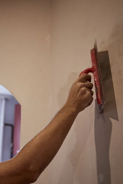 Home renovation: worker processes the wall with putty. True moment ...