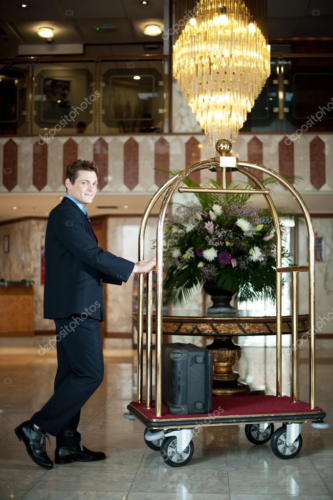 Handsome concierge pushing the luggage cart Stock Photo by ...