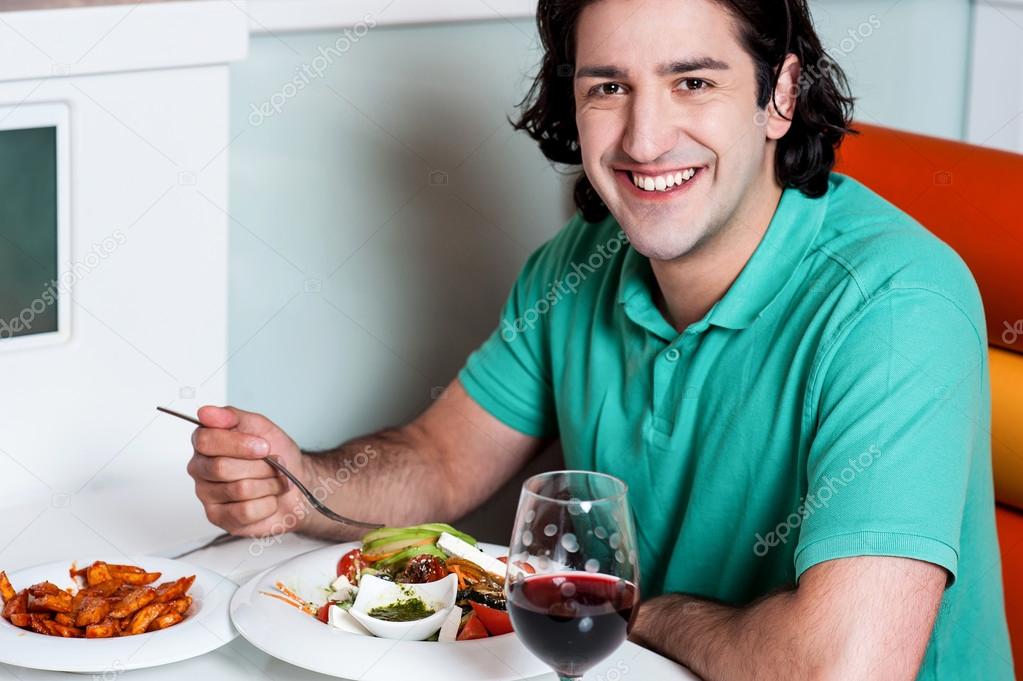 Joven sonriente comiendo en el restaurante 2024