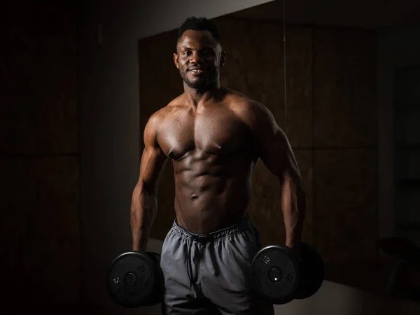 Muscular dark-skinned man doing an exercise with dumbbells. - Stock ...