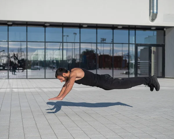 A man in black sportswear jumps while doing push-ups outdoors. - Stock ...