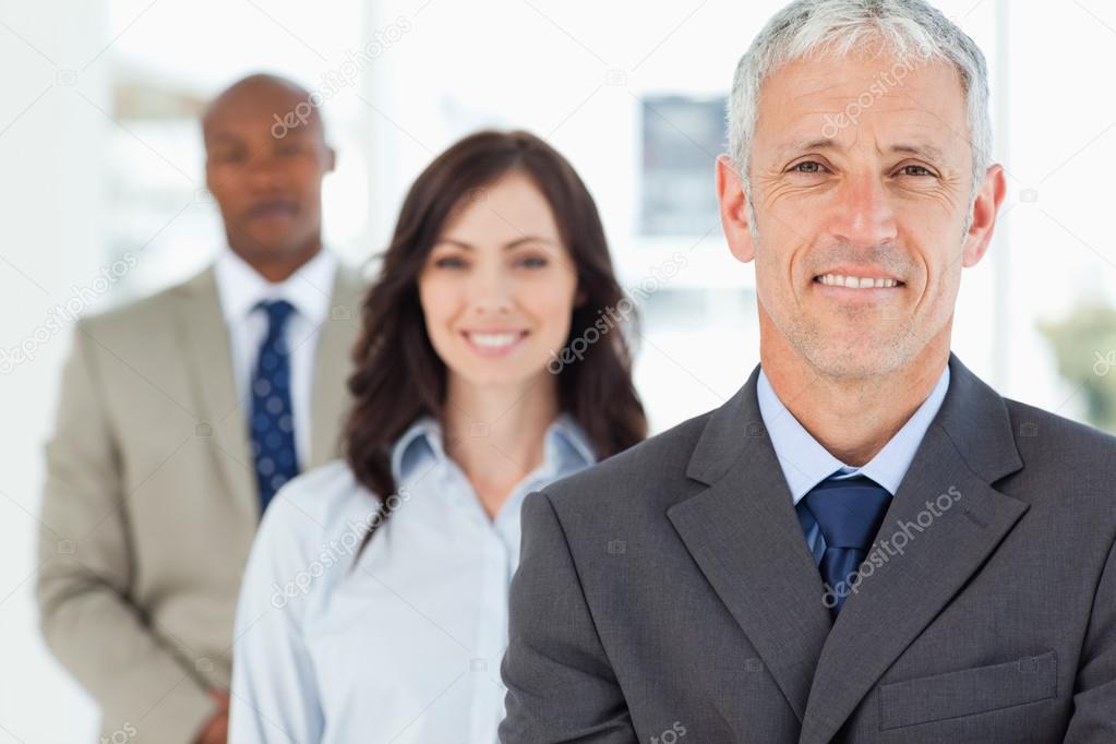 Mature manager smiling while his team is following him Stock Photo by ...