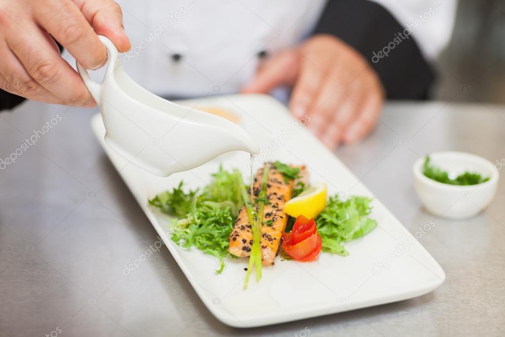 Chef pouring sauce on salmon dish — Stock Photo © Wavebreakmedia #23108626