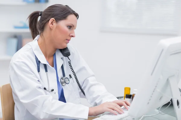 Female doctor using computer while on call at clinic - Stock Image ...