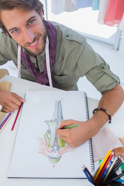 Smiling fashion designer drawing a coat - Stock Image - Everypixel