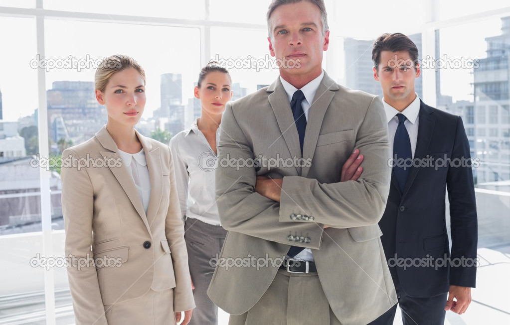 Boss standing with his arms folded with colleagues behind Stock Photo ...