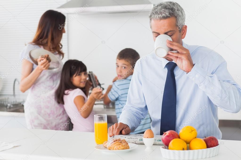 Father drinking coffee while his family are cooking in the kitch Stock ...