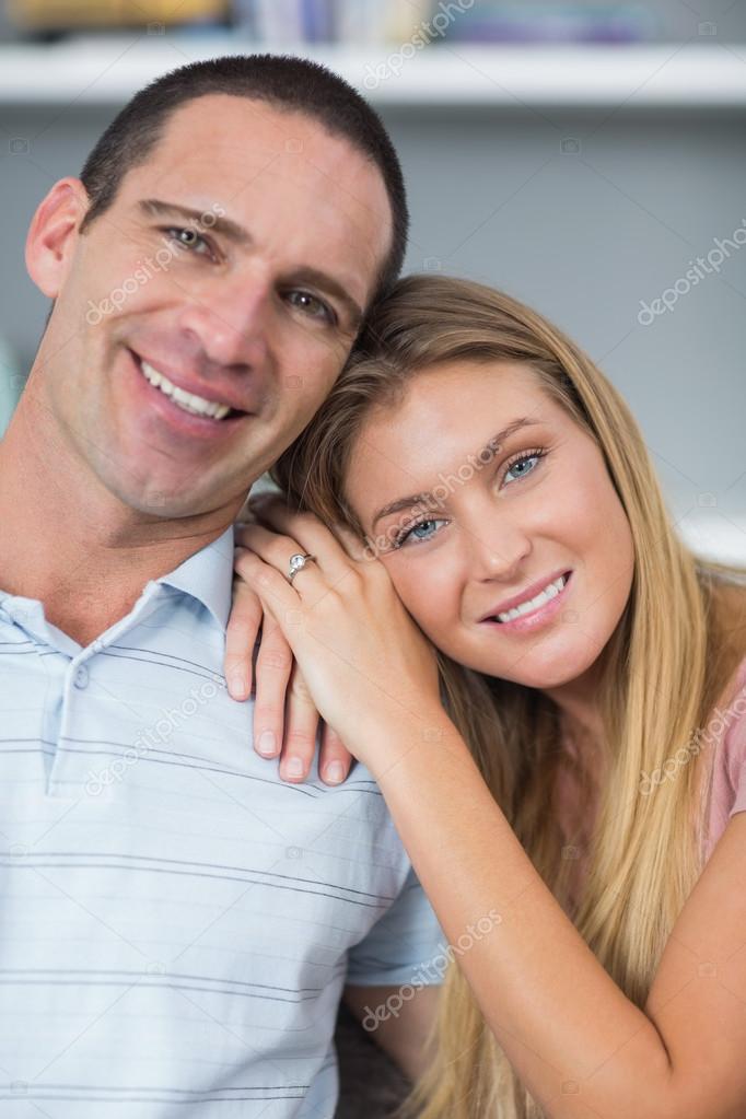 Cute couple sitting on the couch smiling at camera Stock Photo by ...