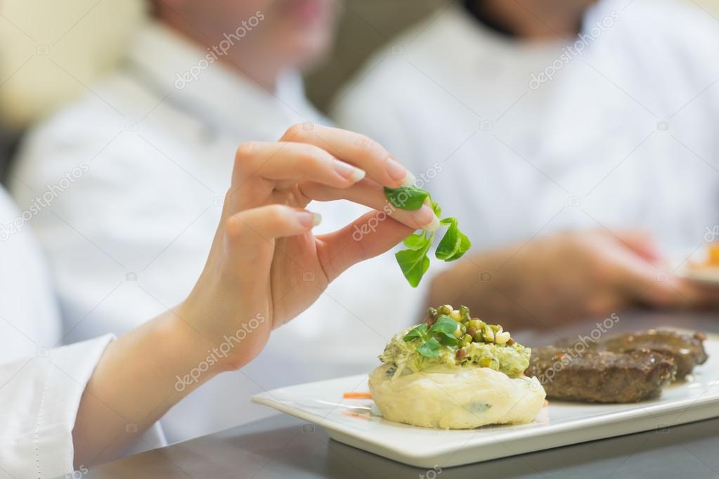 Female chef garnishing a plate with steak — Stock Photo ...