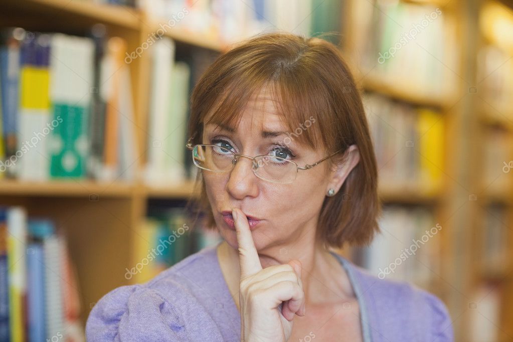 Female librarian giving a sign to be quiet standing in library ⬇ Stock ...