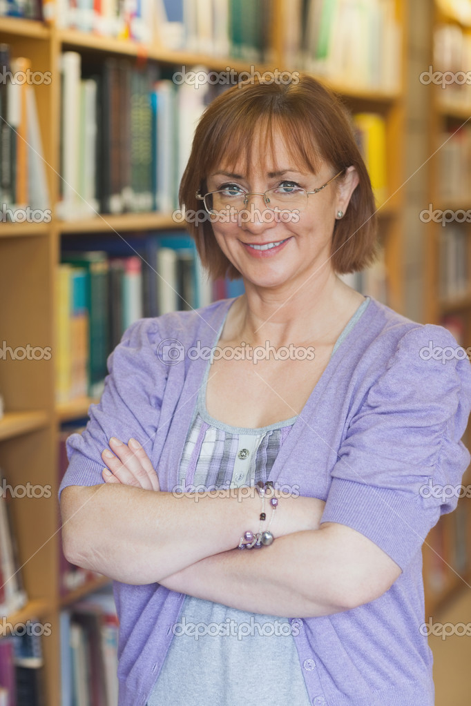 Mature female librarian posing in library with crossed arms Stock Photo ...