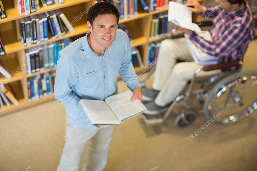Man by disabled student in wheelchair in the library Stock Photo by ...