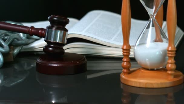 Gavel and handcuffs dropping onto sounding block beside hourglass and ...