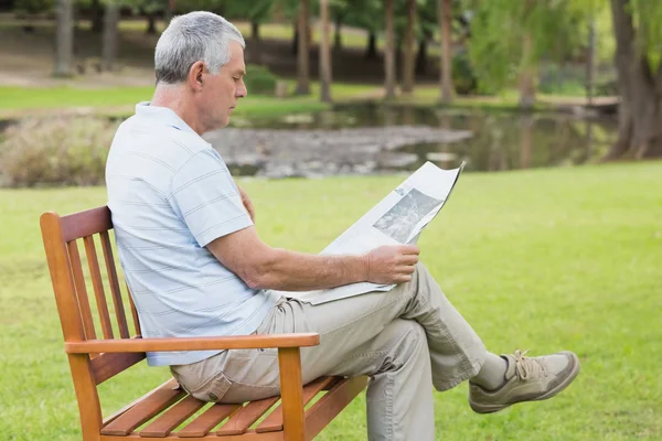 Relaxed senior man reading newspaper at park - Stock Image - Everypixel