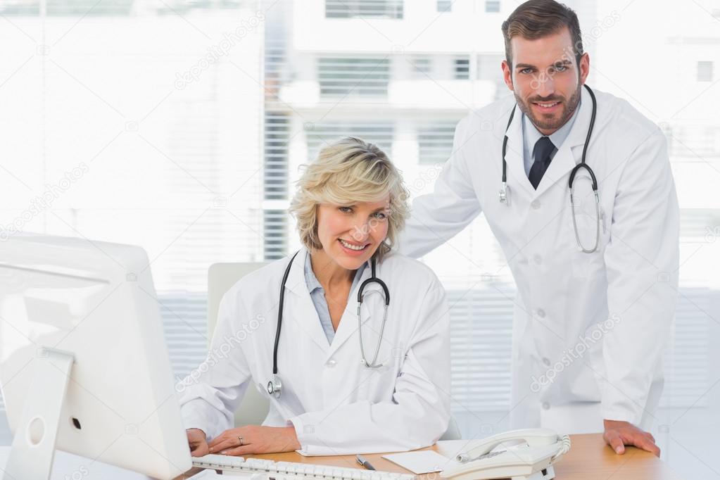 Smiling doctors with computer at medical office Stock Photo by ...