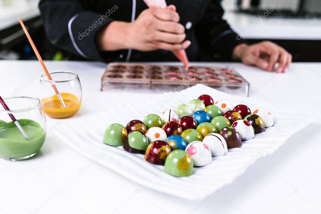 mano de pastelera latina vestida de uniforme negro en proceso de ...
