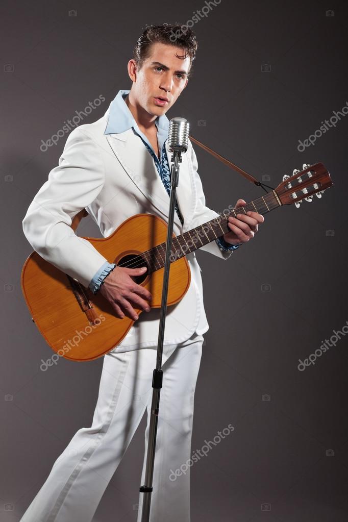 Retro rock and roll singer with guitar wearing white suit. Studi ...