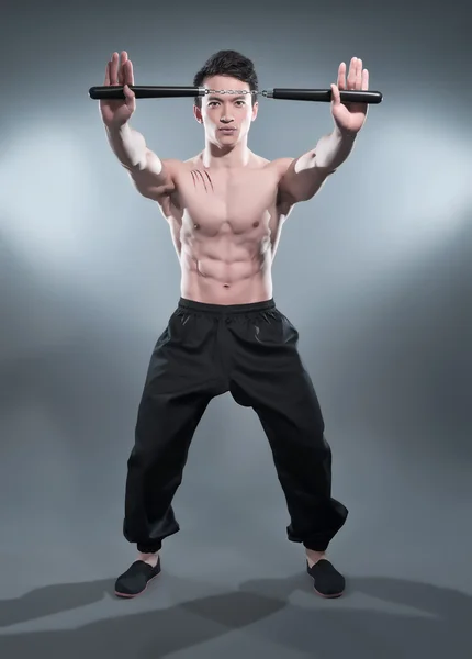 Muscled asian kung fu man in action pose with nunchucks. Blood s Stock ...