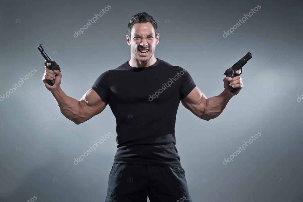 Action hero muscled man holding two guns. Wearing black t-shirt — Stock ...