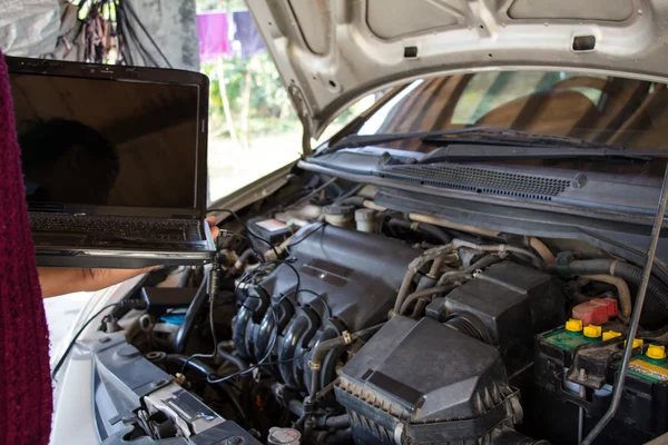 Mechanic with laptop near car engine. Modern car diagnostic program on ...