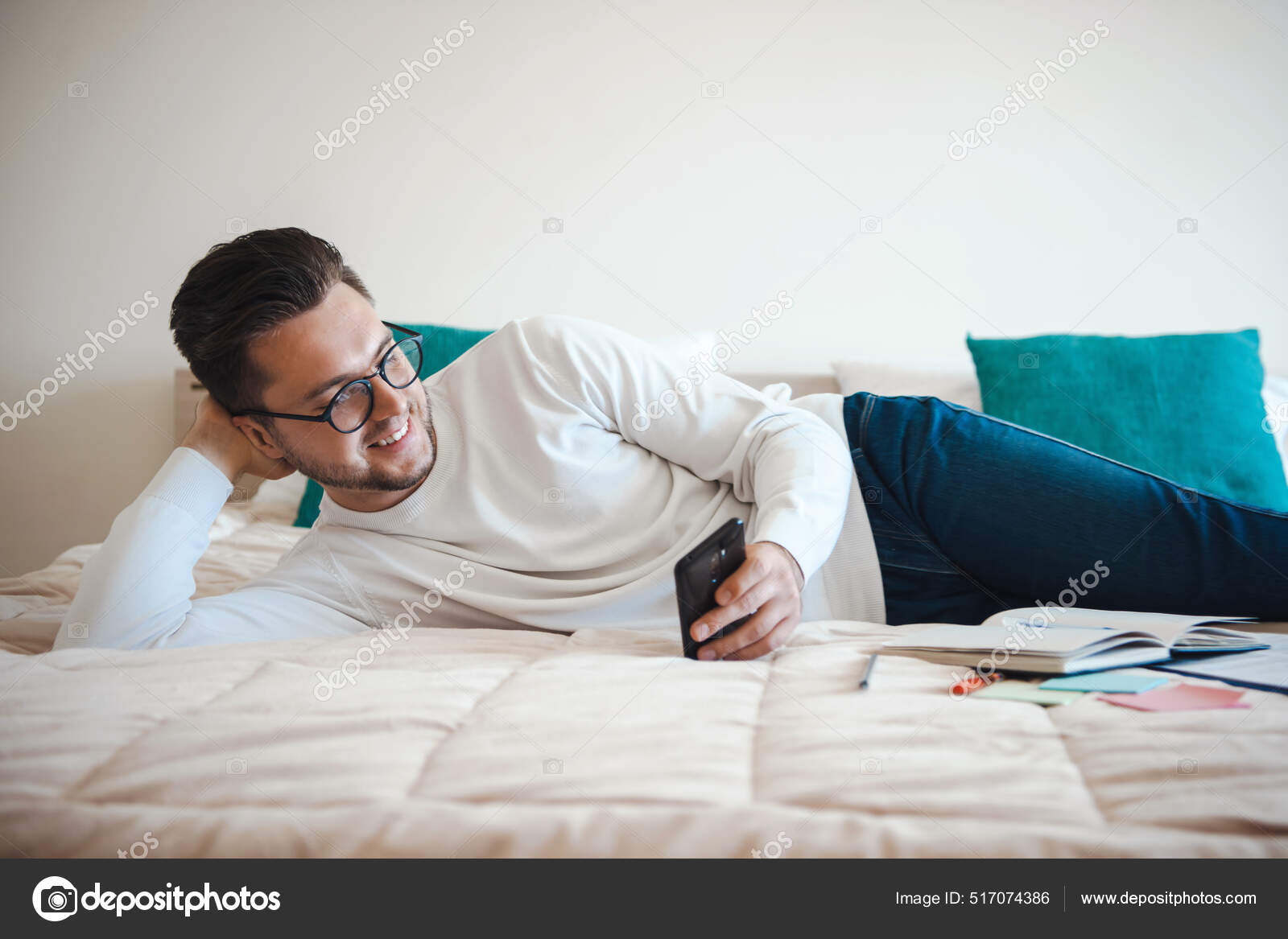 Man lying on one side on the bed with one hand under his head and with ...