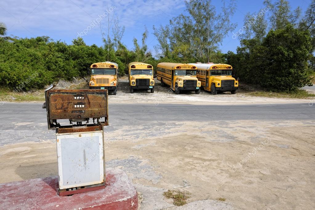 Old rusting fuel pump in front of yellow school buses in Governo ...