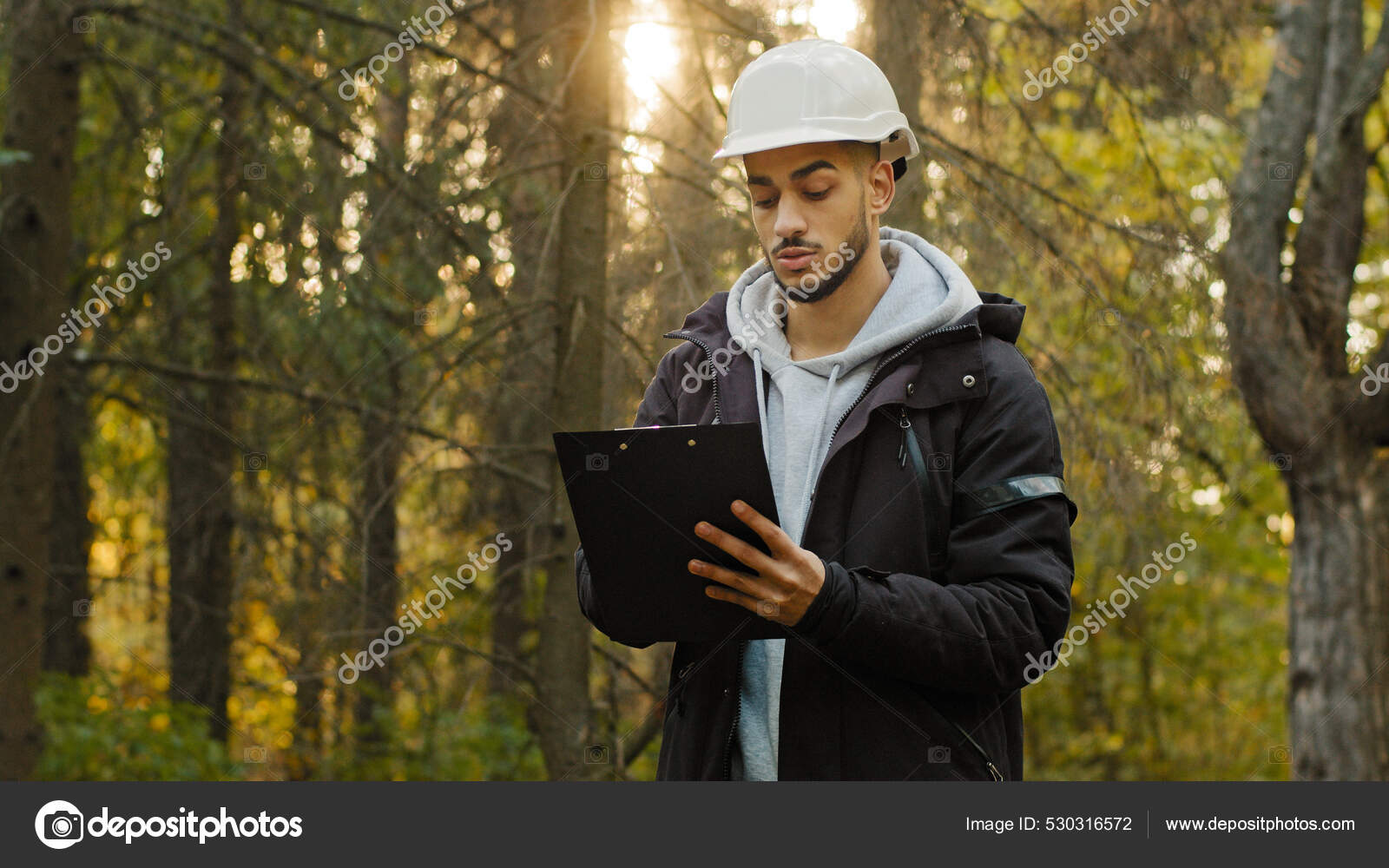 Young experienced Indian man forestry engineer in hardhat with tablet ...