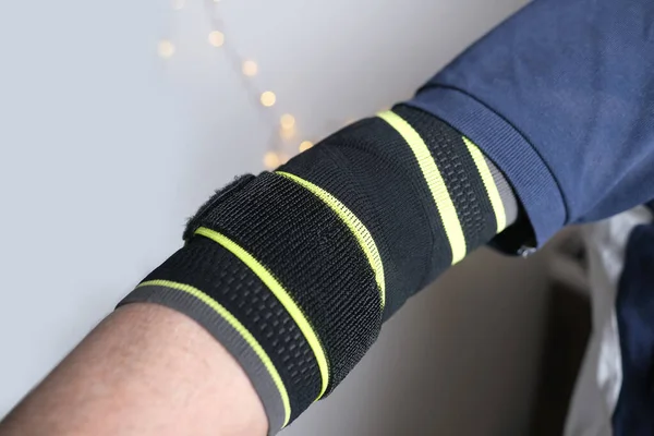close-up of a man's elbow, part of a European's hand in a black elastic ...