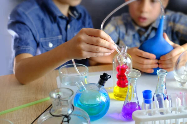 dos niños de 7 a 9 años, niños de escuela primaria, hacen experimentos químicos, vierten ...