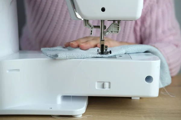close-up of female hands perform work on a white sewing electric ...